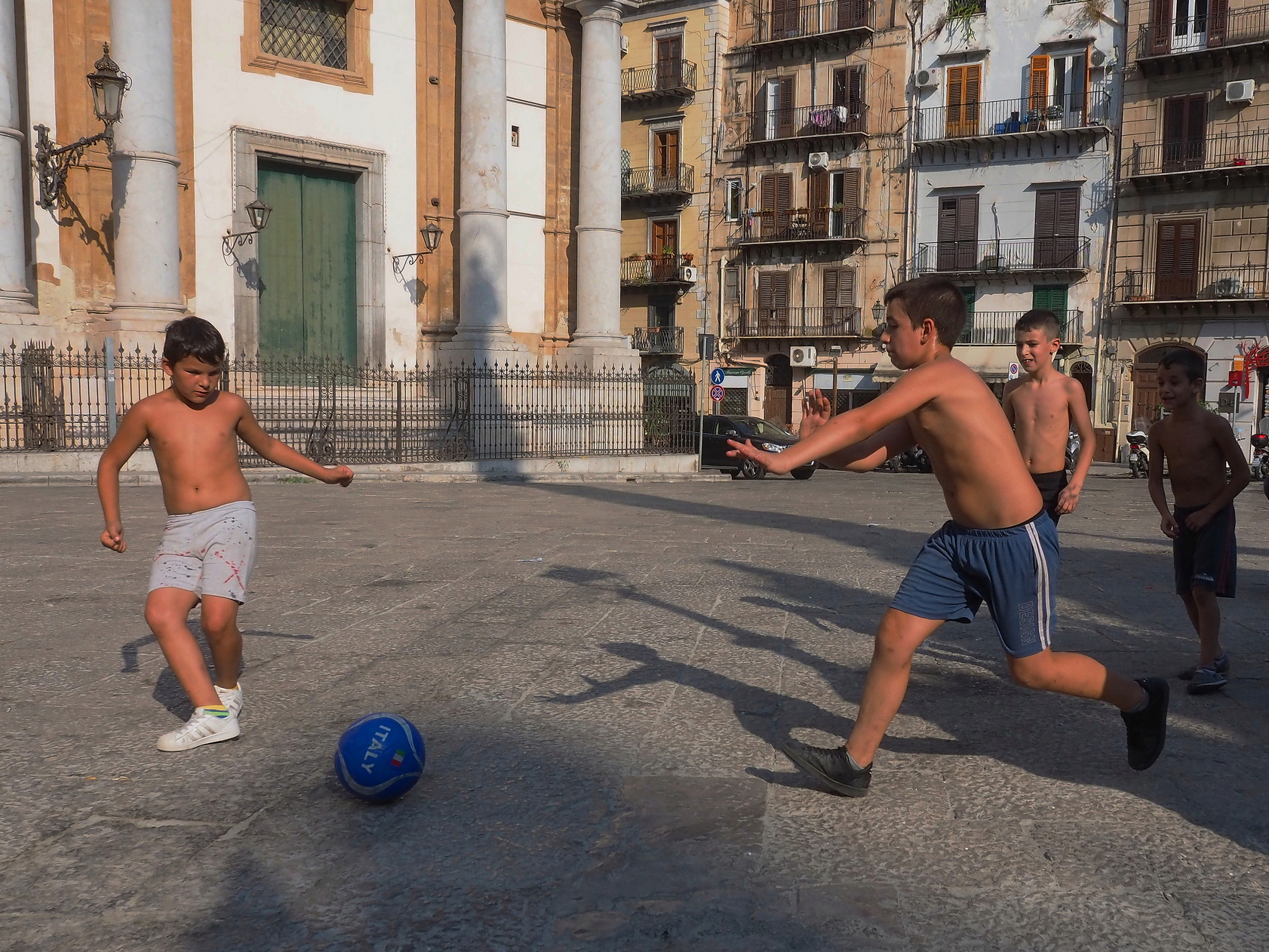 Children playing soccer on the street 1 - Exibart Street